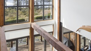 Um quarto com pé direito alto e grandes janelas com vista para uma área arborizada.