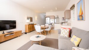 Uma sala moderna com televisão de tela plana, móveis de madeira, área de jantar e cozinha.
