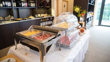 Uma mesa de buffet com diversos alimentos e uma seleção de vinhos.