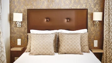 Quarto de hotel com uma cama grande, duas mesas de cabeceira e parede com padrão.