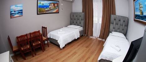Quarto de hotel com duas camas, uma mesa de jantar com cadeiras e obras de arte nas paredes.