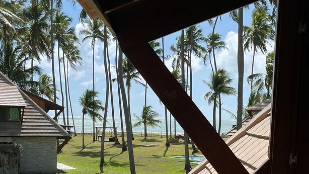 Uma varanda com vista para palmeiras e o oceano.