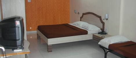 Quarto de hotel com cama, escrivaninha e televisão, e mesa de cabeceira.