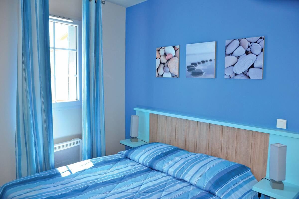 Um quarto com uma cama, uma mesa de cabeceira e um alto-falante fixado na parede.