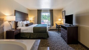 Quarto de hotel com cama, escrivaninha, televisão, cômoda e banheira.