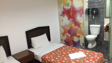 Quarto de hotel com duas camas, chuveiro e sanitário.