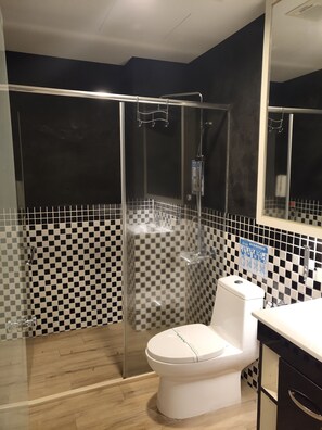 Um banheiro moderno com chuveiro envidraçado, vaso sanitário branco e painel de azulejos xadrez.