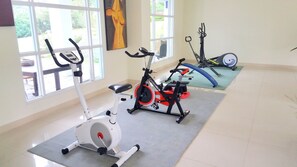 Academia com bicicletas ergométricas, uma máquina de remo e esteira.