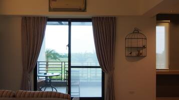 Quarto espaçoso com uma cama grande, varanda com mesa e cadeiras, e vista para o exterior.