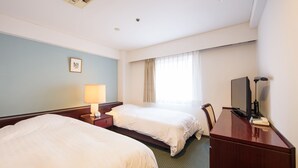 Quarto de hotel com duas camas, uma escrivaninha com luminária, televisão e janela com cortinas.