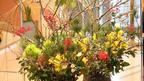 Uma planta em vaso com flores amarelas e vermelhas e folhagem verde.