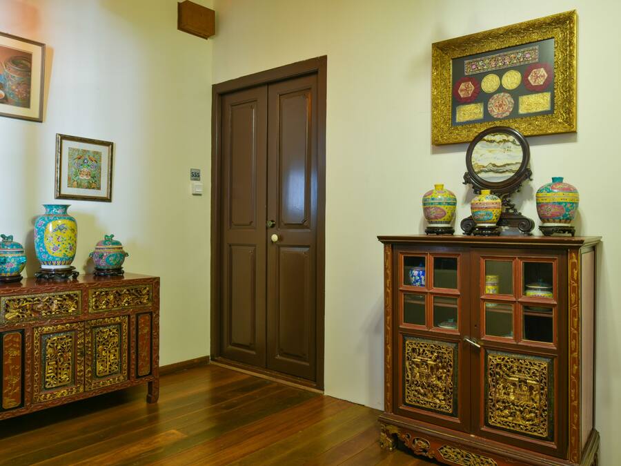 Um corredor com porta de madeira, um armário com vasos decorativos e obras de arte emolduradas nas paredes.