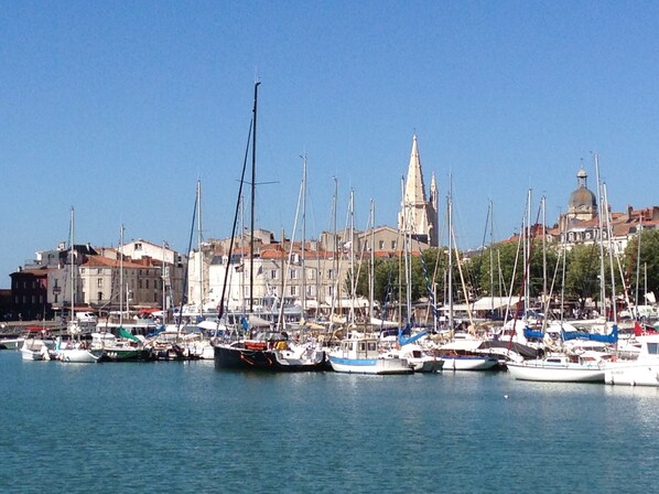 Uma marina com vários barcos atracados, uma igreja imponente com uma torre alta e uma estrutura em cúpula ao fundo.