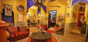 Um interior marroquino tradicional com um sofá estampado, uma mesa redonda e um abajur decorativo.