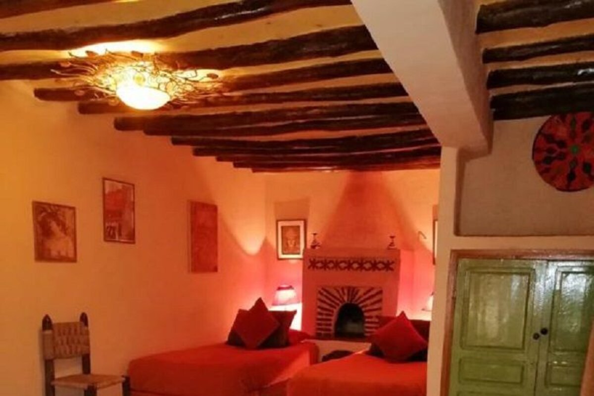 Um quarto acolhedor com uma cama, dois sofás vermelhos, uma pequena mesa e uma porta verde.