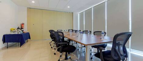 Sala de conferência com uma mesa comprida, cadeiras e um projetor.