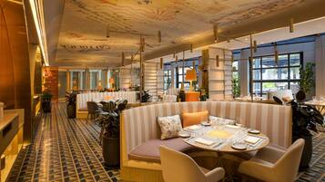 Um restaurante moderno com assentos em cabines listradas, piso estampado e teto com desenhos artísticos.