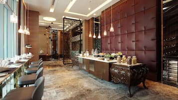 Um restaurante moderno com um balcão extenso, diversas áreas de estar e uma parede decorativa.
