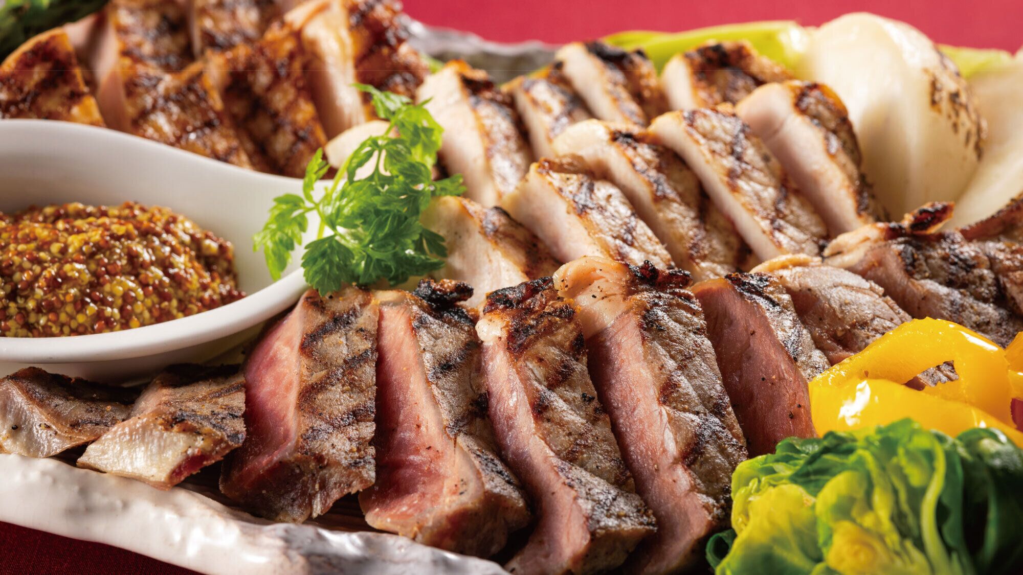 Prato com carne fatiada, acompanhado de molho e legumes.