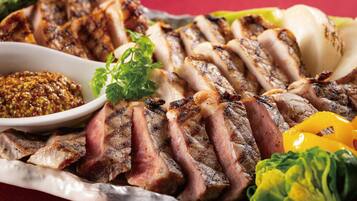 Prato com carne fatiada, acompanhado de molho e legumes.