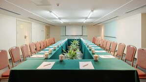 Uma sala de conferências com uma mesa comprida, cadeiras e um projetor.