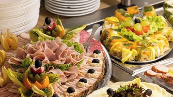 Buffet com diversos itens de comida, incluindo carnes, queijos e saladas.