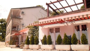Um edifício com varanda, plantas em vasos e toldo vermelho.