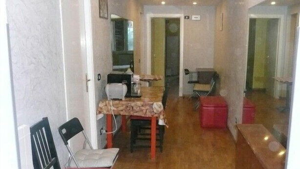 Um corredor estreito com uma sala de jantar, com uma mesa e cadeiras.