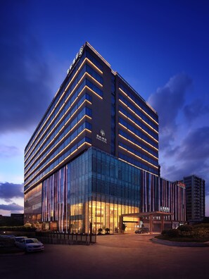 Edifício moderno de hotel com fachada de vidro e linhas iluminadas.