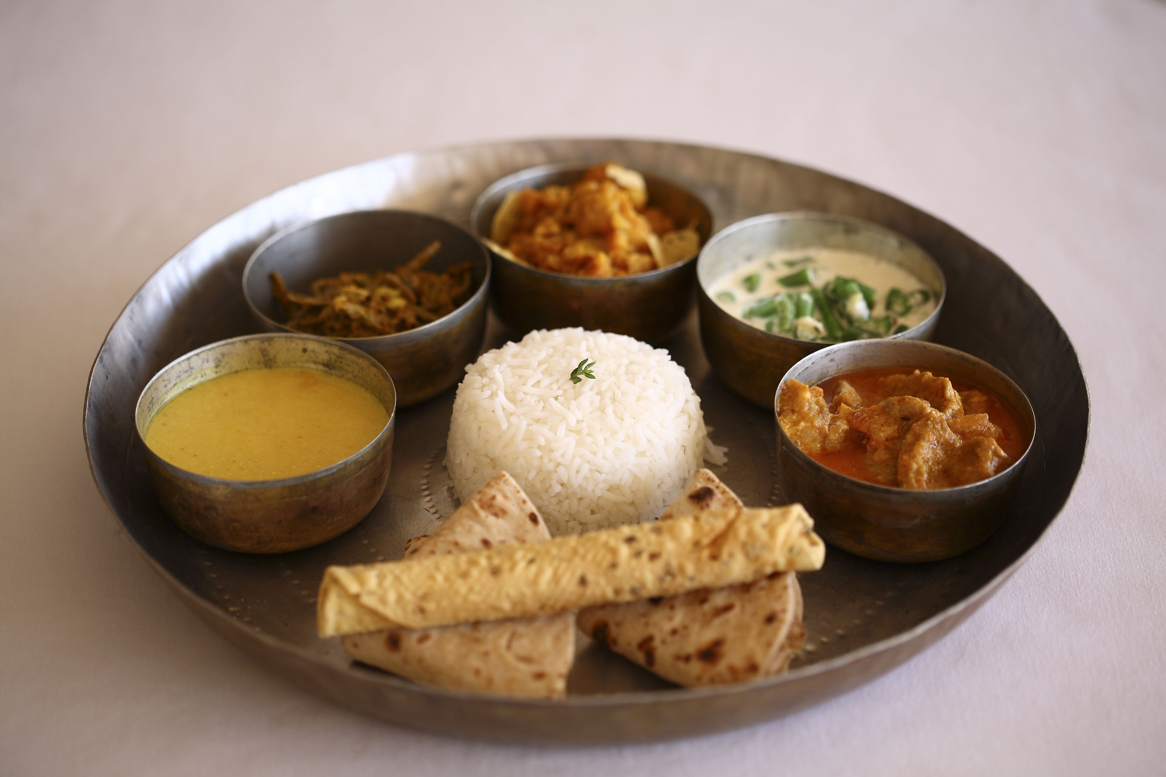 Um prato com arroz branco, chapati e diversos curries.