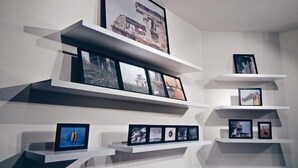 Uma galeria com várias prateleiras brancas exibindo fotografias emolduradas.
