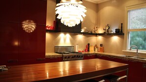 Uma cozinha moderna com ilha central, eletrodomésticos de aço inoxidável e um lustre singular.
