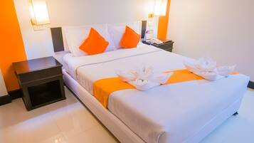 Quarto de hotel com uma cama grande, duas mesas de cabeceira e uma luminária fixada na parede.