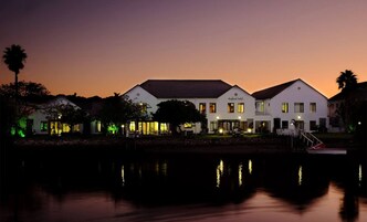 Um hotel à beira-mar com vários edifícios, um cais e um lago calmo que reflete as estruturas.