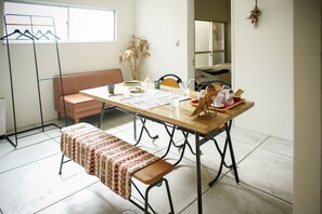 Uma área de refeições com uma mesa de madeira, bancos e um banco com capa estampada.
