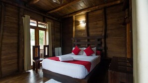 Quarto de cabana de madeira com uma cama grande, uma mesinha de cabeceira e uma janela com cortinas.