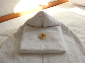 Toalha branca dobrada com etiqueta Hotel Hasen sobre a cama.