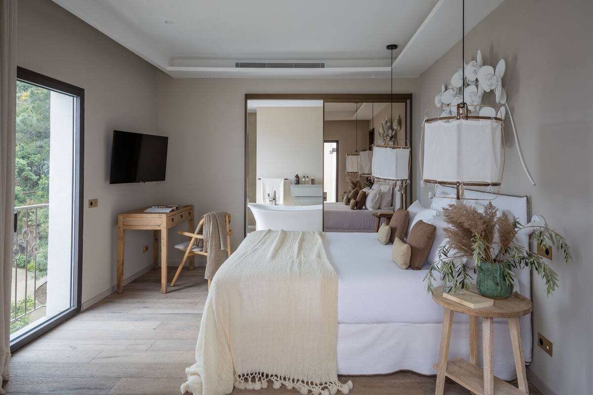 Quarto com uma cama grande, uma escrivaninha, uma televisão e vista para o exterior.