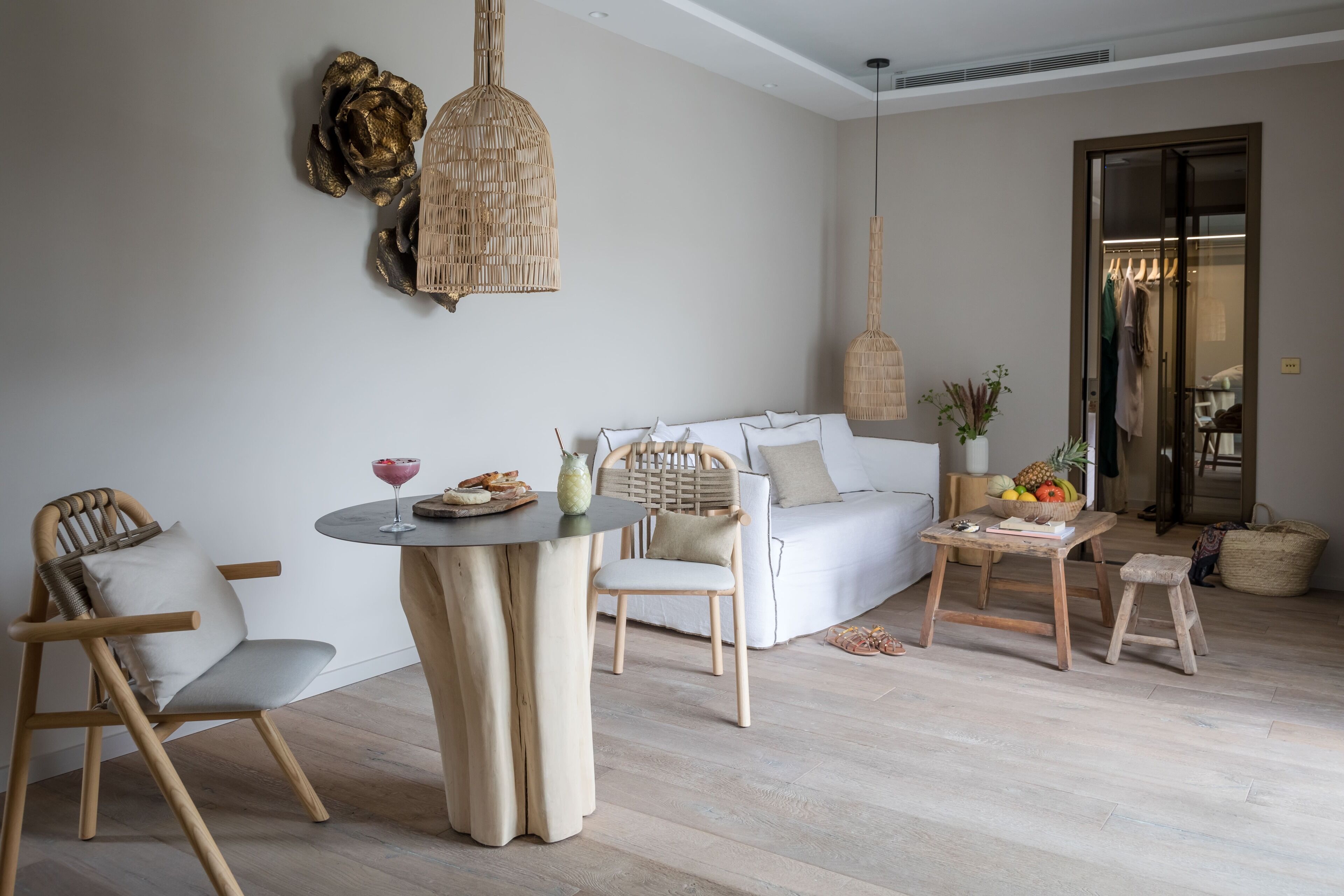 Uma sala de estar moderna com uma mesa redonda, duas cadeiras, um sofá e uma pequena mesa lateral com frutas.