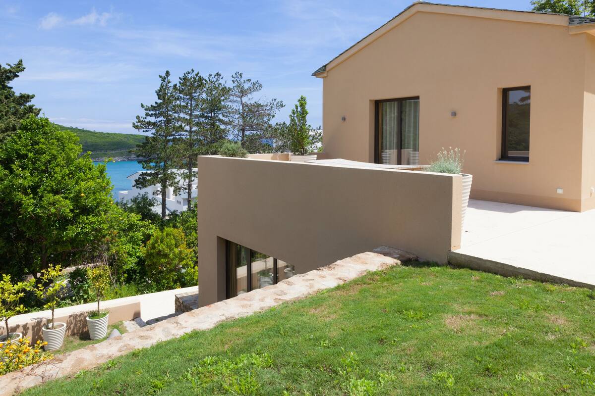 Uma casa moderna com telhado plano, janelas amplas e vista para o mar.