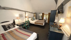 Quarto de hotel com duas camas, uma escrivaninha e uma cadeira.
