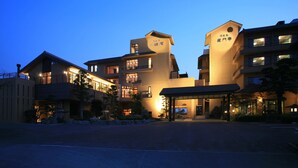 Um hotel com vários andares e design arquitetônico moderno, com uma entrada em destaque e área de espera coberta.