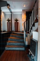Escadaria moderna com guarda-corpo de vidro, que leva a um patamar com duas grandes plantas em vasos.