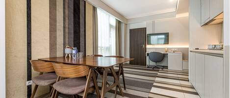 Quarto de hotel moderno com área de refeições, cozinha e uma grande janela.