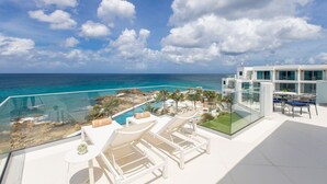 Um hotel moderno com uma piscina infinita de vidro com vista para o oceano, cadeiras de lounge e uma vista clara do mar.