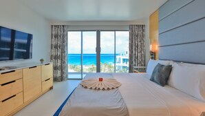 Quarto de hotel com cama grande, televisão e vista para o oceano.