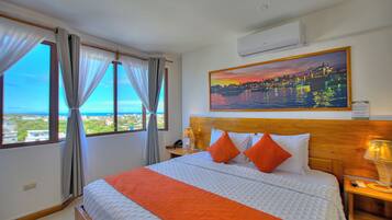 Quarto de hotel com uma cama grande, um quadro de uma paisagem urbana e vista para a cidade pela janela.