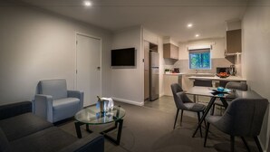 Uma sala de estar moderna com uma mesa de centro de vidro, um sofá e um espaço de jantar com cadeiras.