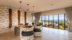 Uma sala de estar moderna com uma parede de pedra, uma escrivaninha de madeira e uma janela grande com vista para a paisagem.