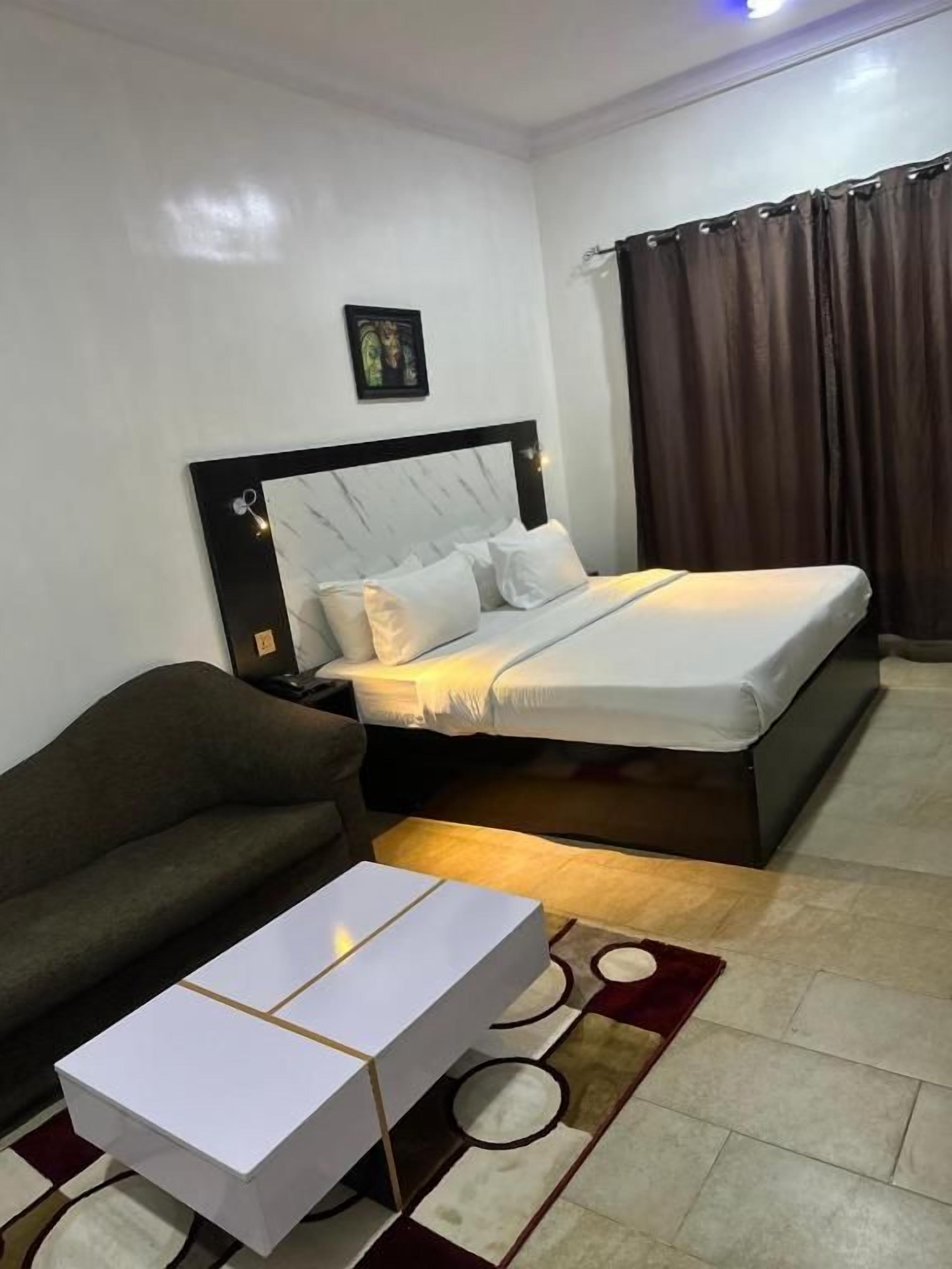Quarto com cama, sofá e mesa de cabeceira.
